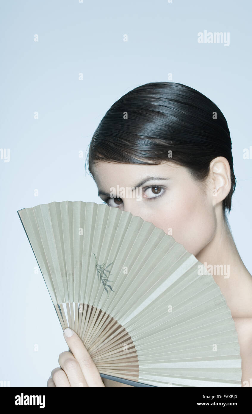 Woman holding fan in front of her face, portrait Stock Photo - Alamy