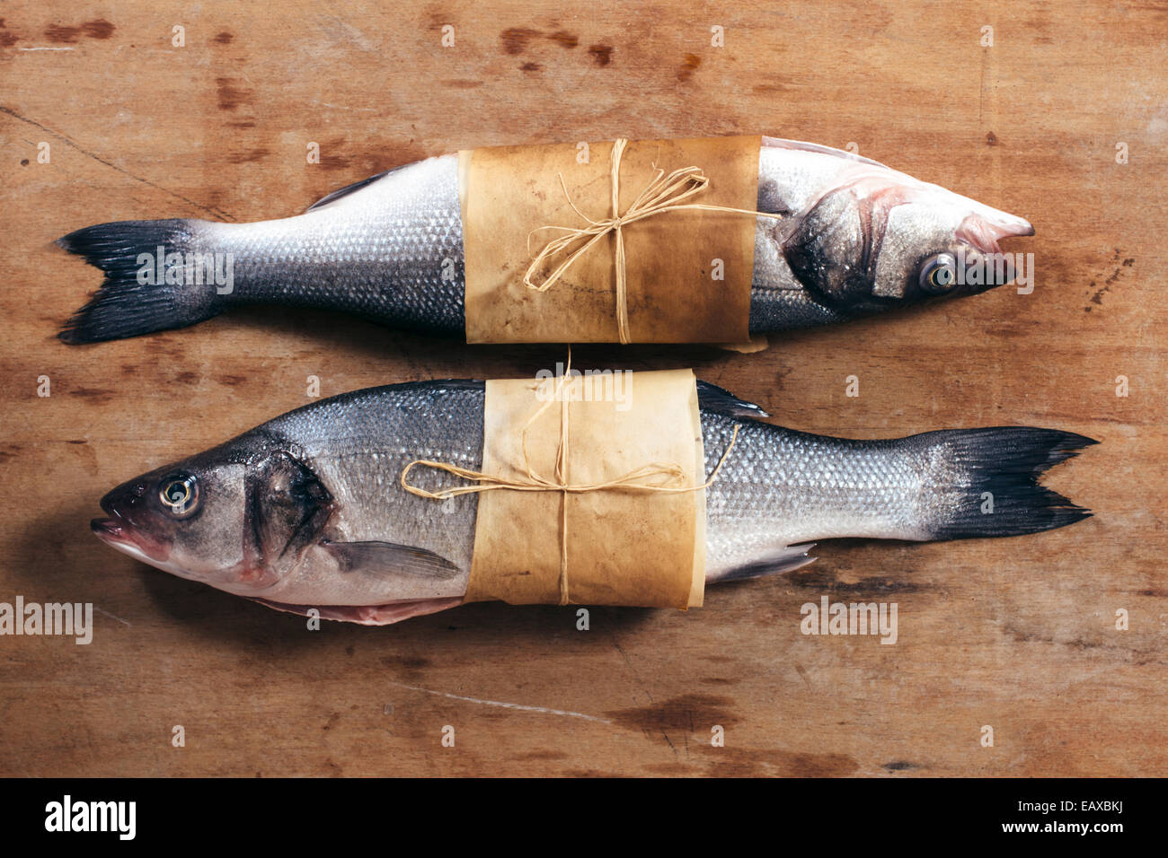 Couple of raw bass fish on the wooden background Stock Photo - Alamy