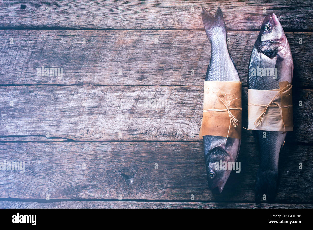 Two raw bass fish on wooden background with blank space Stock Photo - Alamy