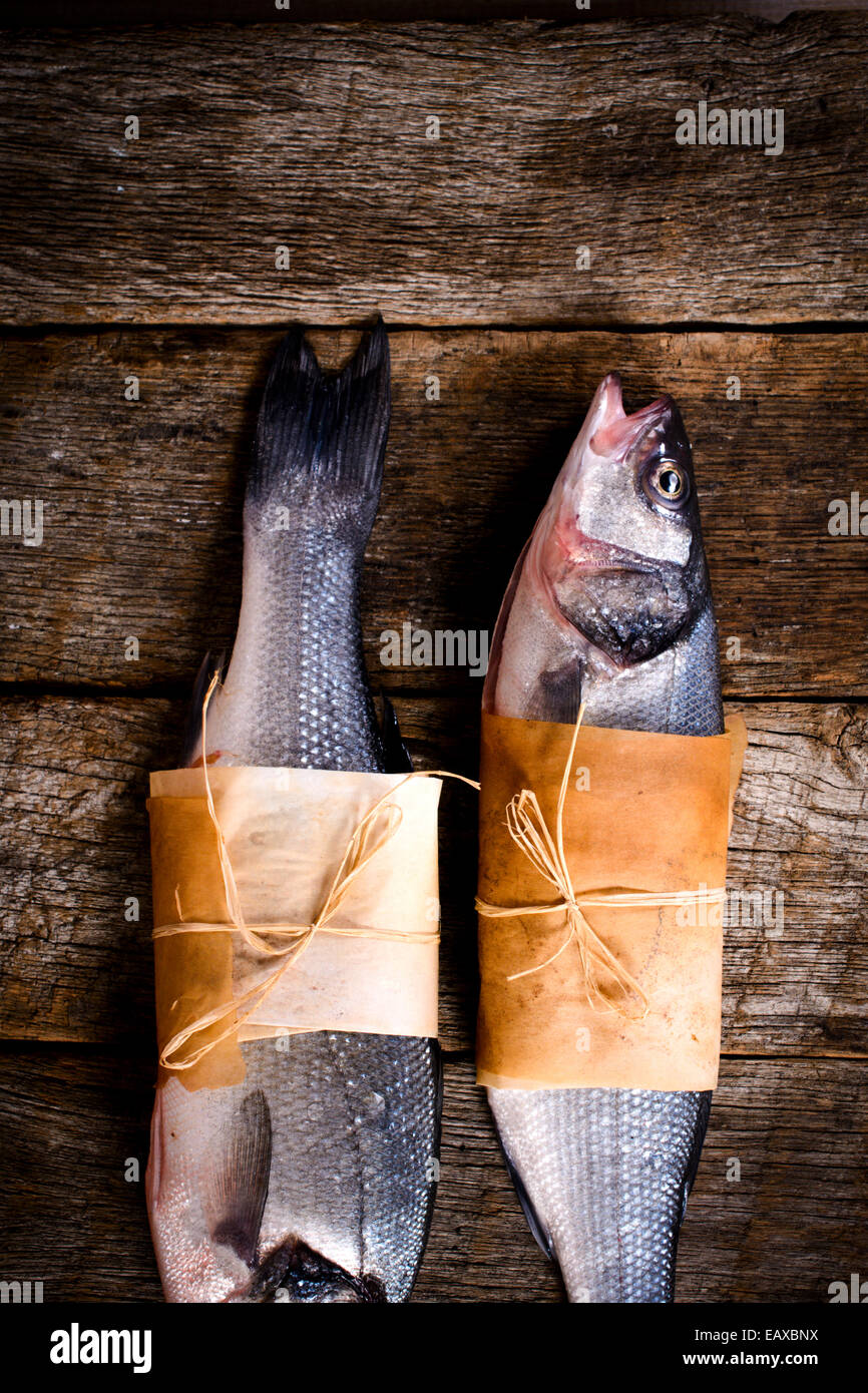 Two raw bass fish on wooden background and blank space Stock Photo - Alamy