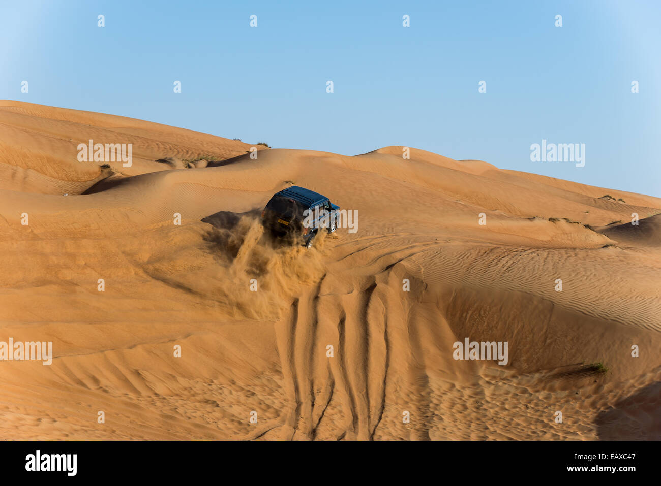 A four-wheel drive jeep driving over sand dunes in the desert of Oman ...
