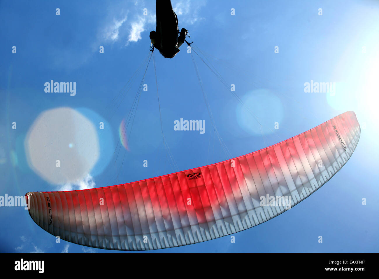 Lens flare as a Paraglider flies past the sun while enjoying flying ...