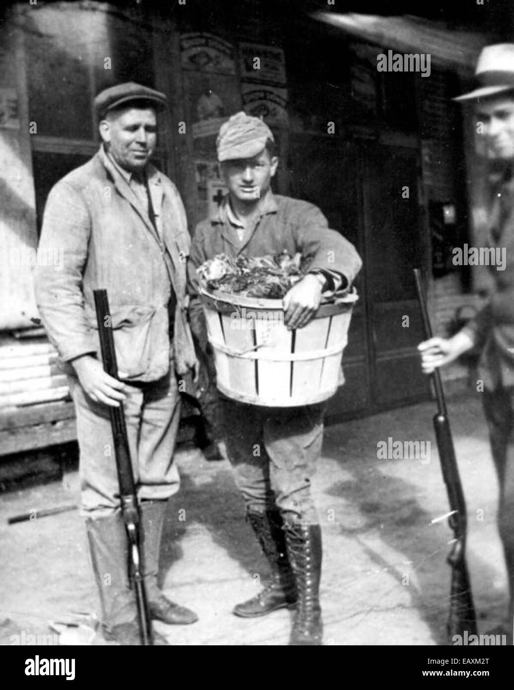 This historical photograph depicts men with a basket of hunter quail ...