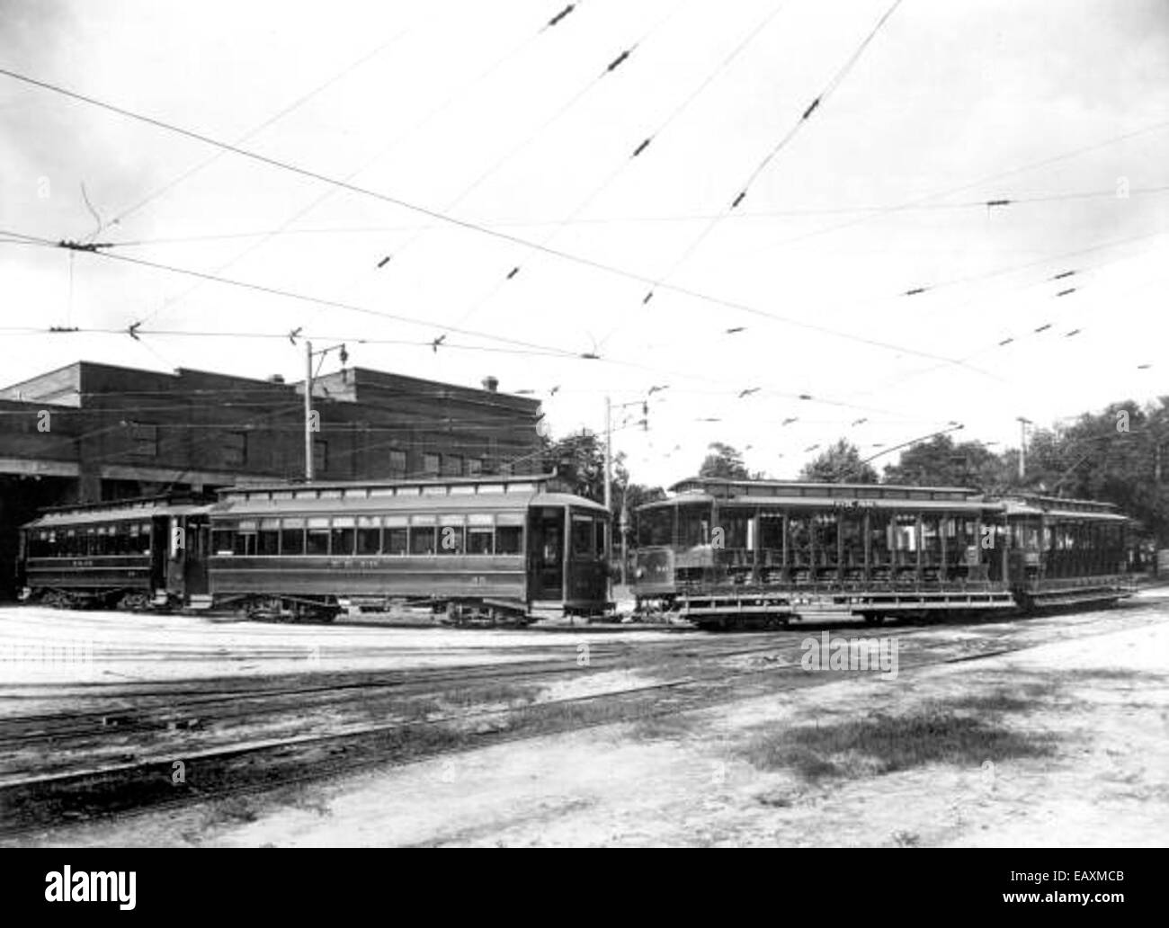 This historical photograph captures streetcars parked in a yard near a ...