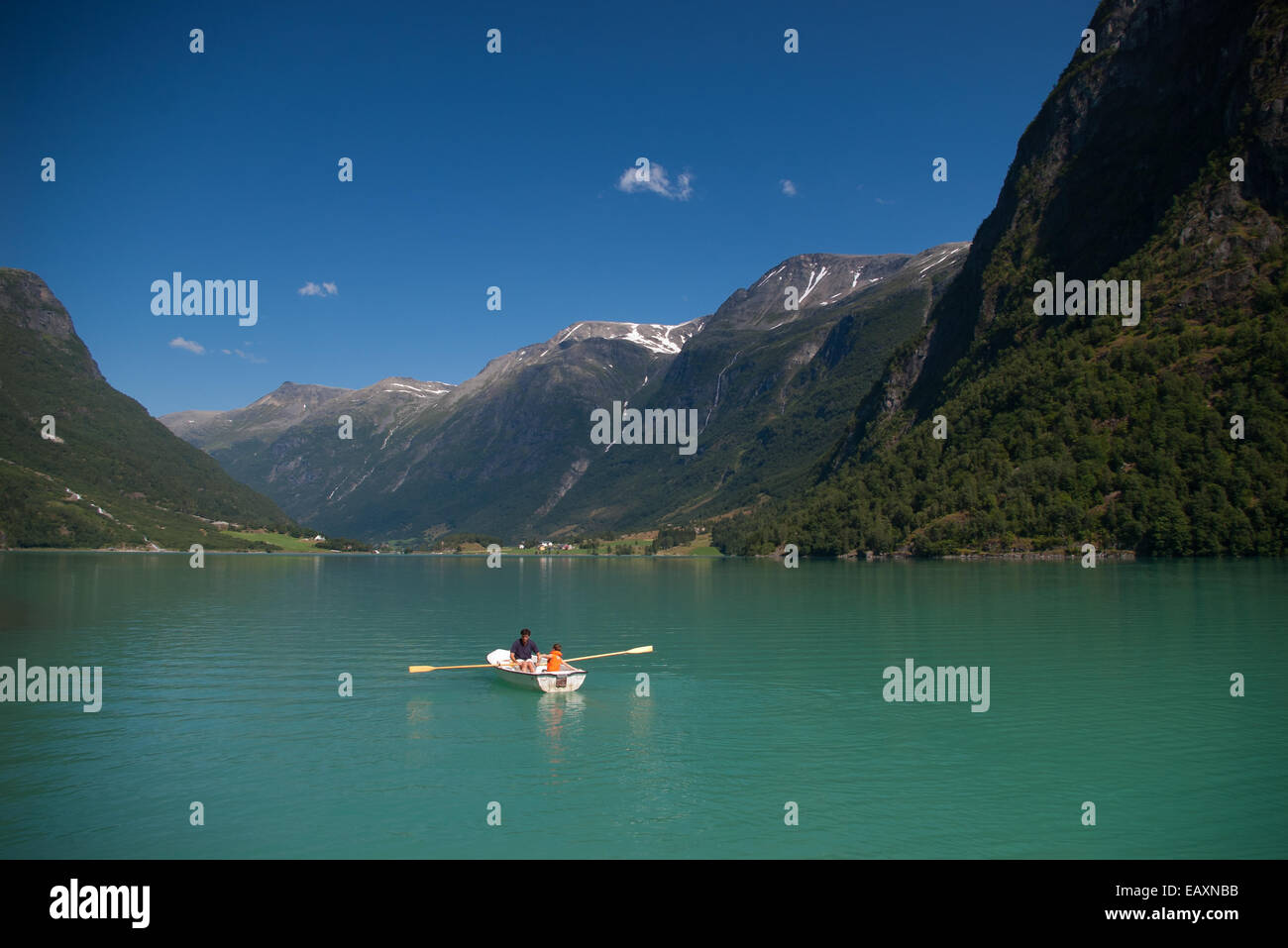 Father and son rowing on lake between mountains in Briksdalen, Norway ...