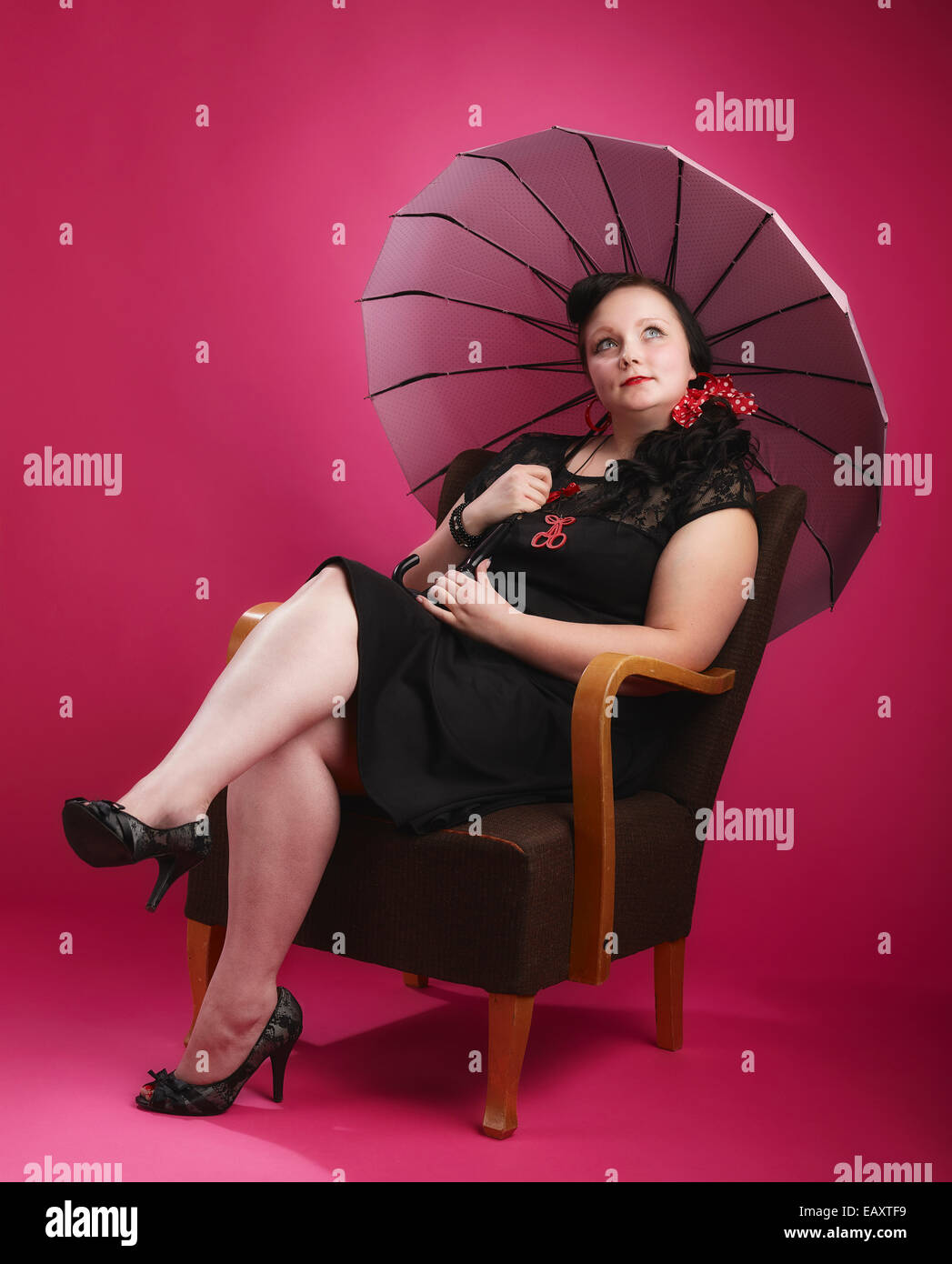 Happy pin-up girl sitting on old retro chair, pink background Stock ...