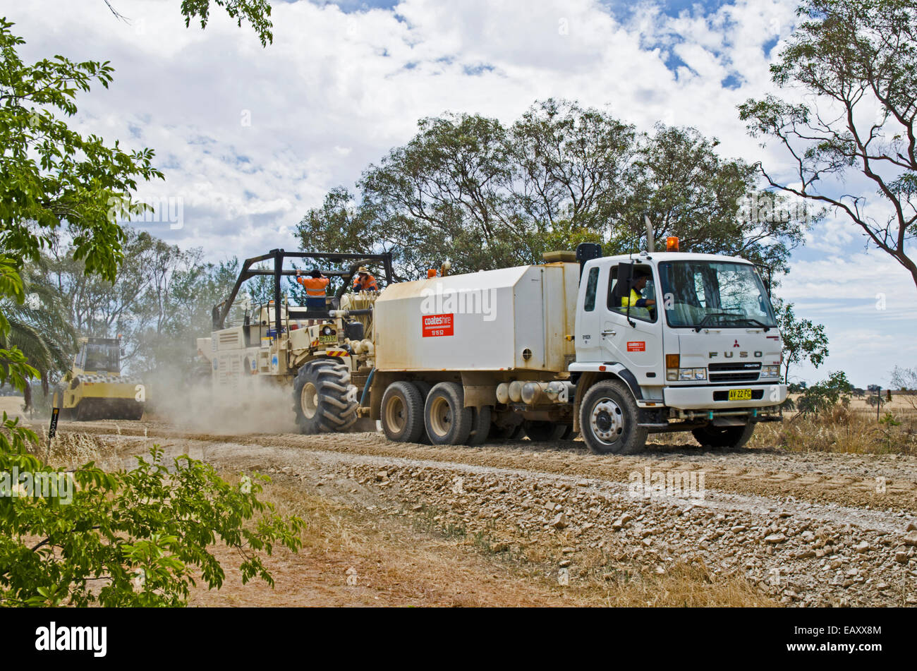 Road building. Water truck preceding the stabilizer followed by the ...