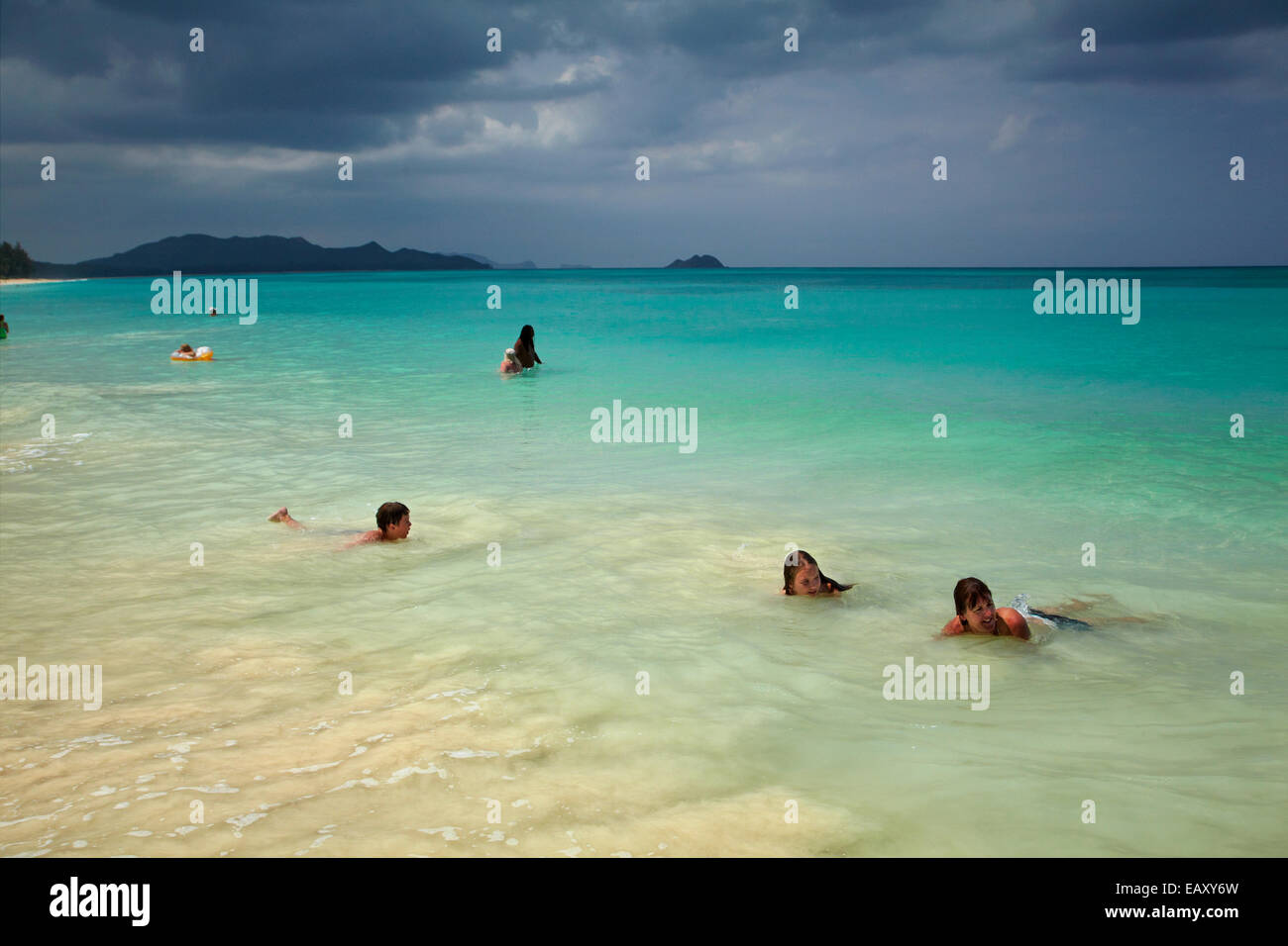 People swimming at Waimanalo Beach, and storm clouds, Oahu, Hawaii, USA ...