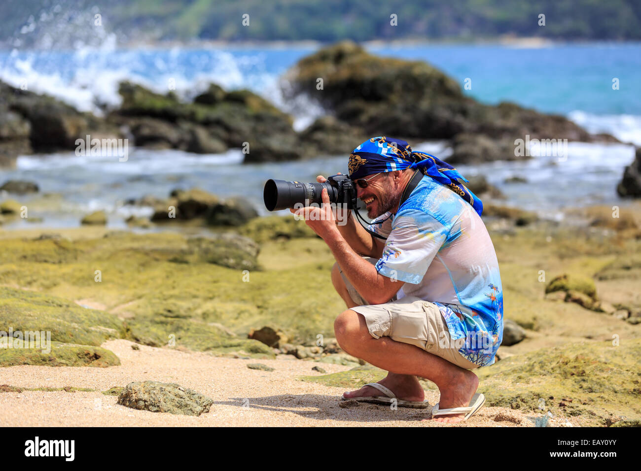 Male photographer looking through a DSLR camera ready for action on the beach Stock Photo - Alamy