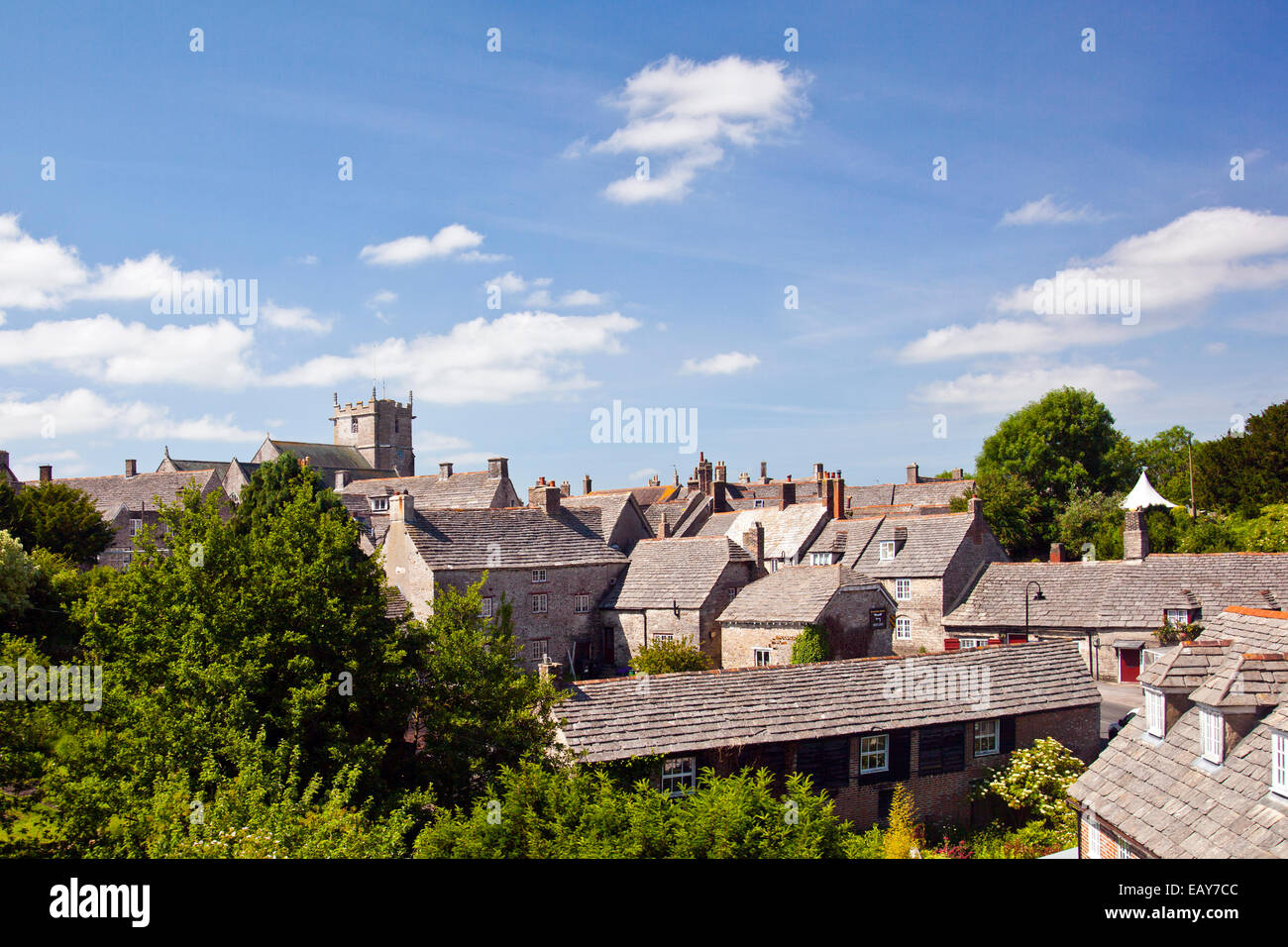 The stone tiled roof tops and parish church at Corfe Castle village ...