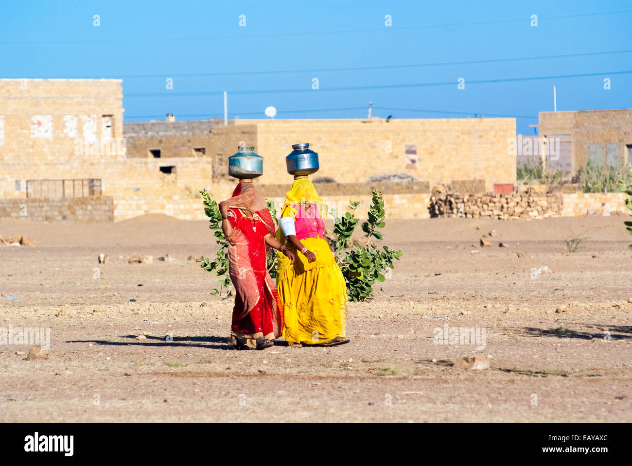 Women lugging a water pot on their head to fetch water from a natural ...