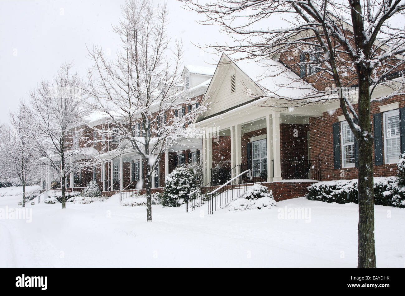 A traditional, brick home is captured during a snow storm in this ...