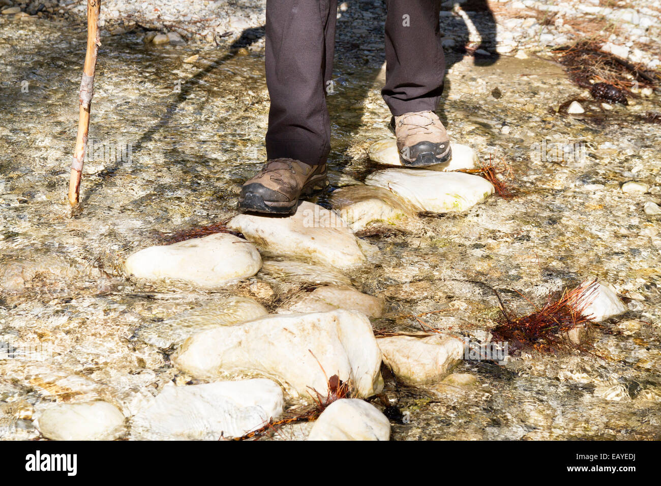 Walker / hiker crossing a small stream in the Spanish hills of Sierra ...