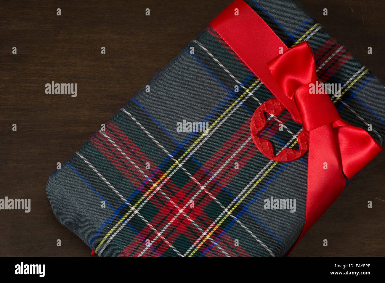 present, wrapped in plaid, red tie and decorative star on dark wood ...
