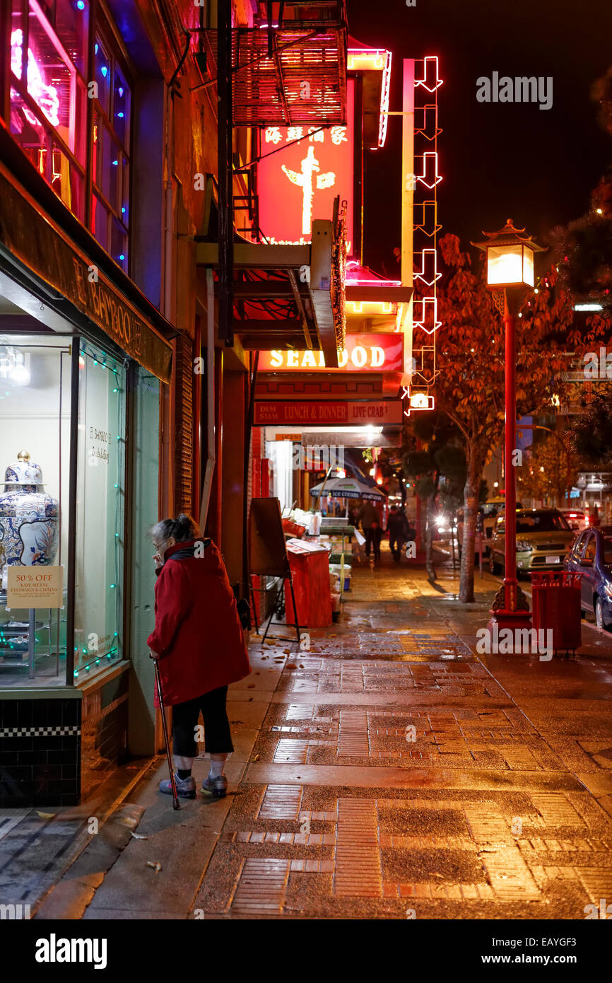 Woman checking storefront window on rainy night-Victoria, British ...