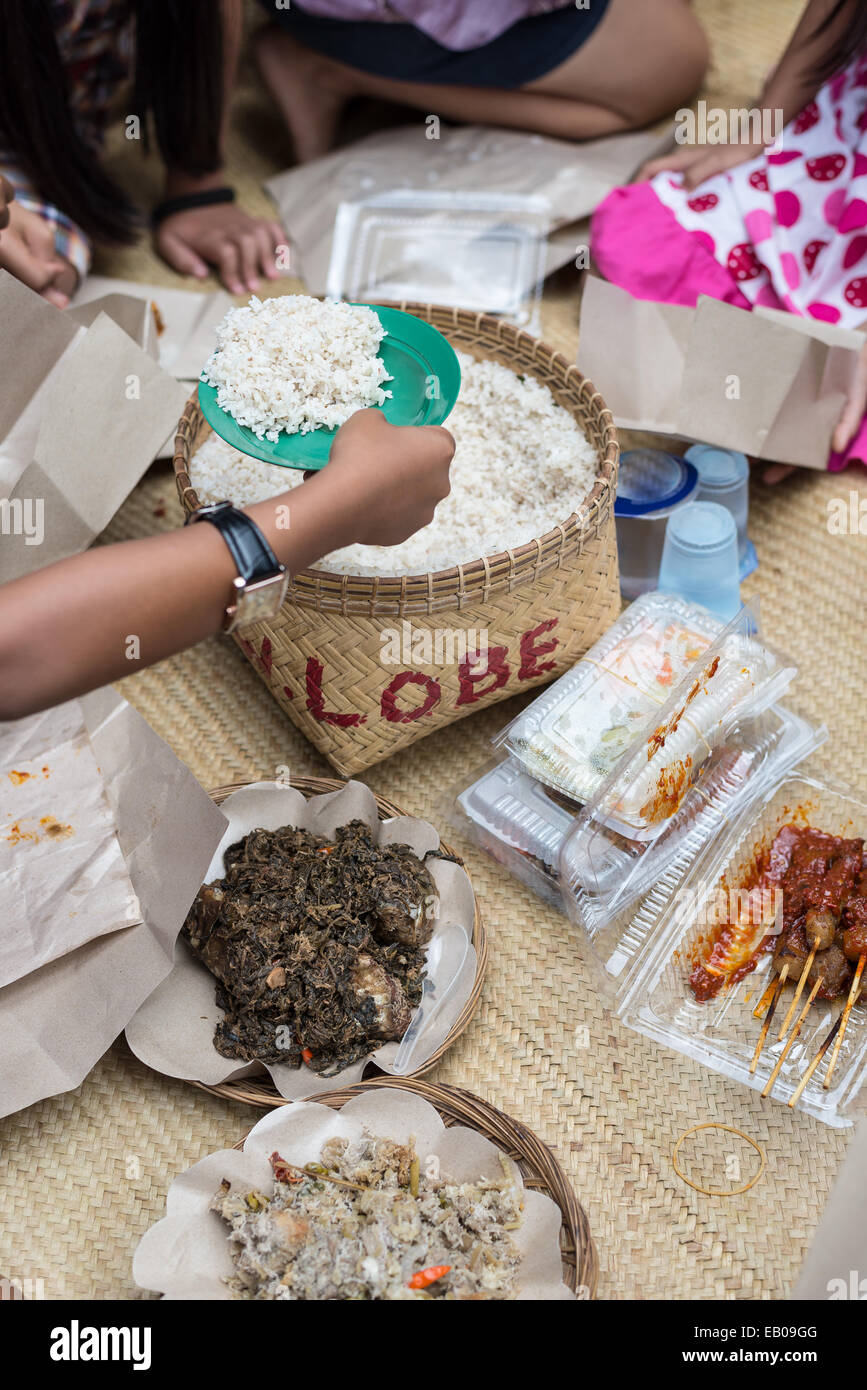 Human hands offering food. Rice basket and meat char grilled inside ...
