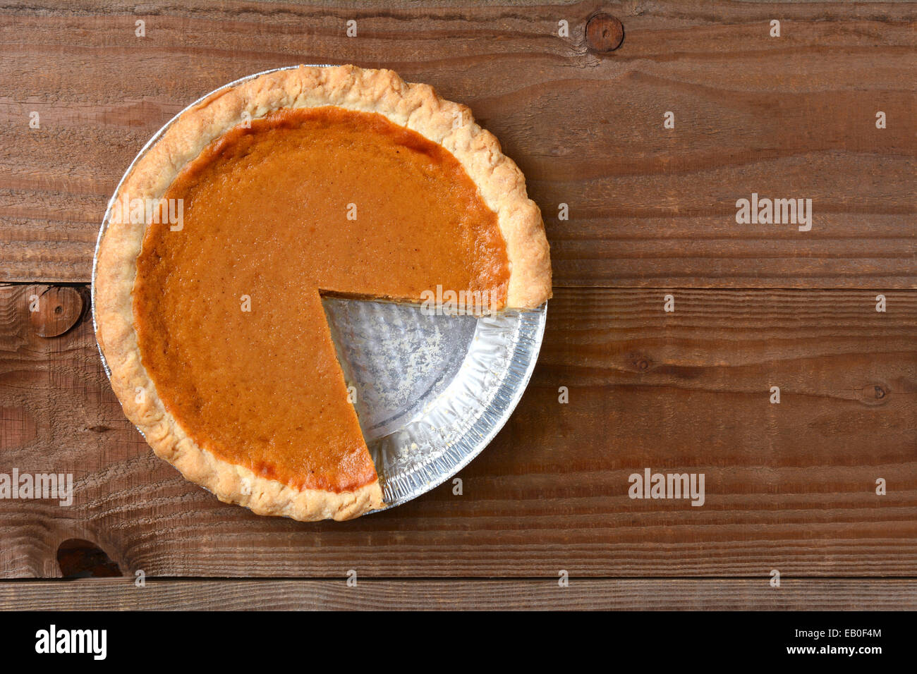 A pumpkin pie with a slice cut out. Horizontal format on a rustic wood ...