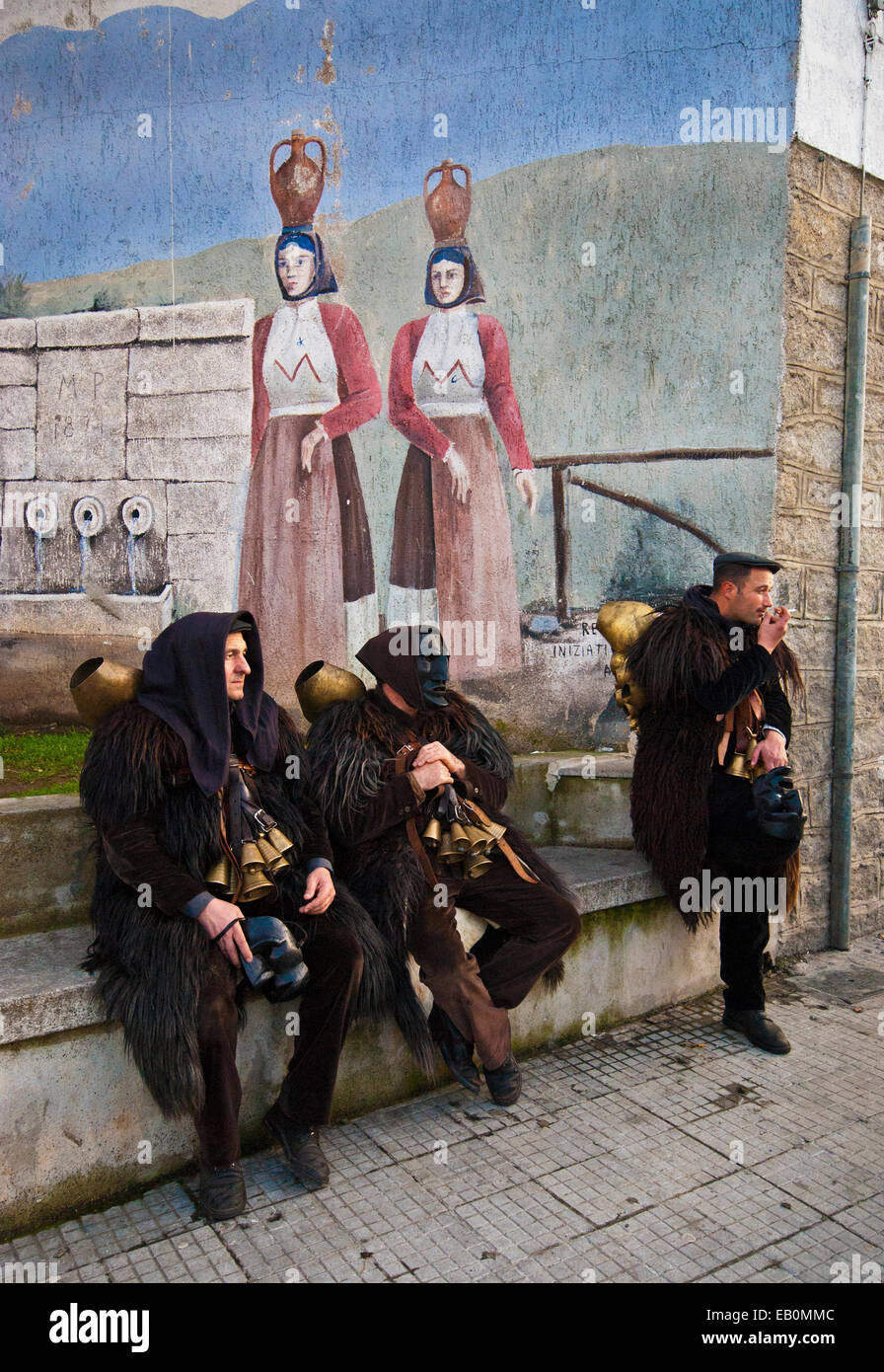 Men wearing traditional old Mammuthones mask during a break near mural ...