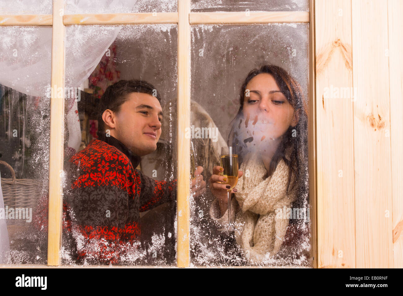 View through the cold frosted window of a young couple celebrating in a ...