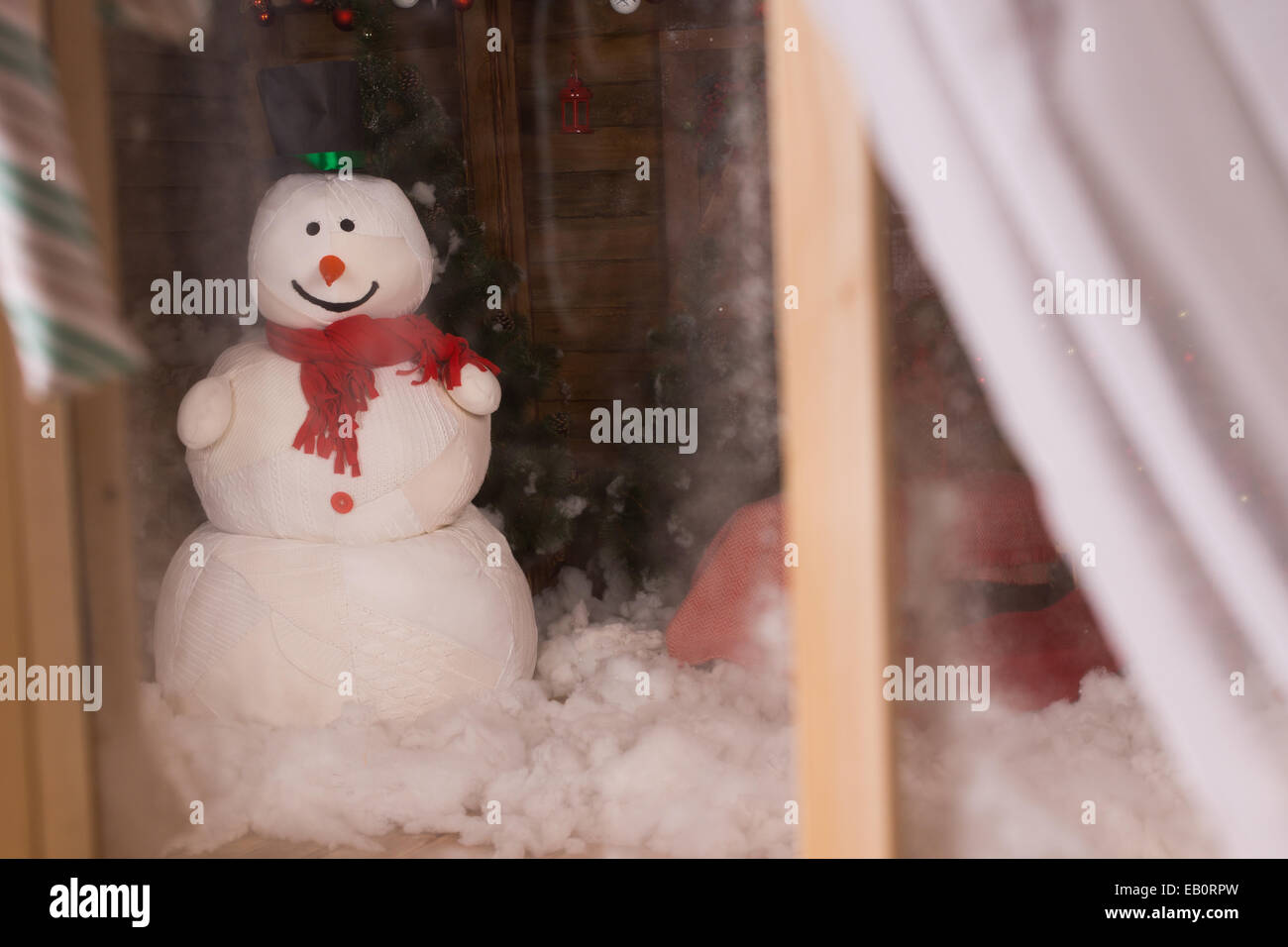 Christmas snowman viewed through a frosted window with open curtain ...