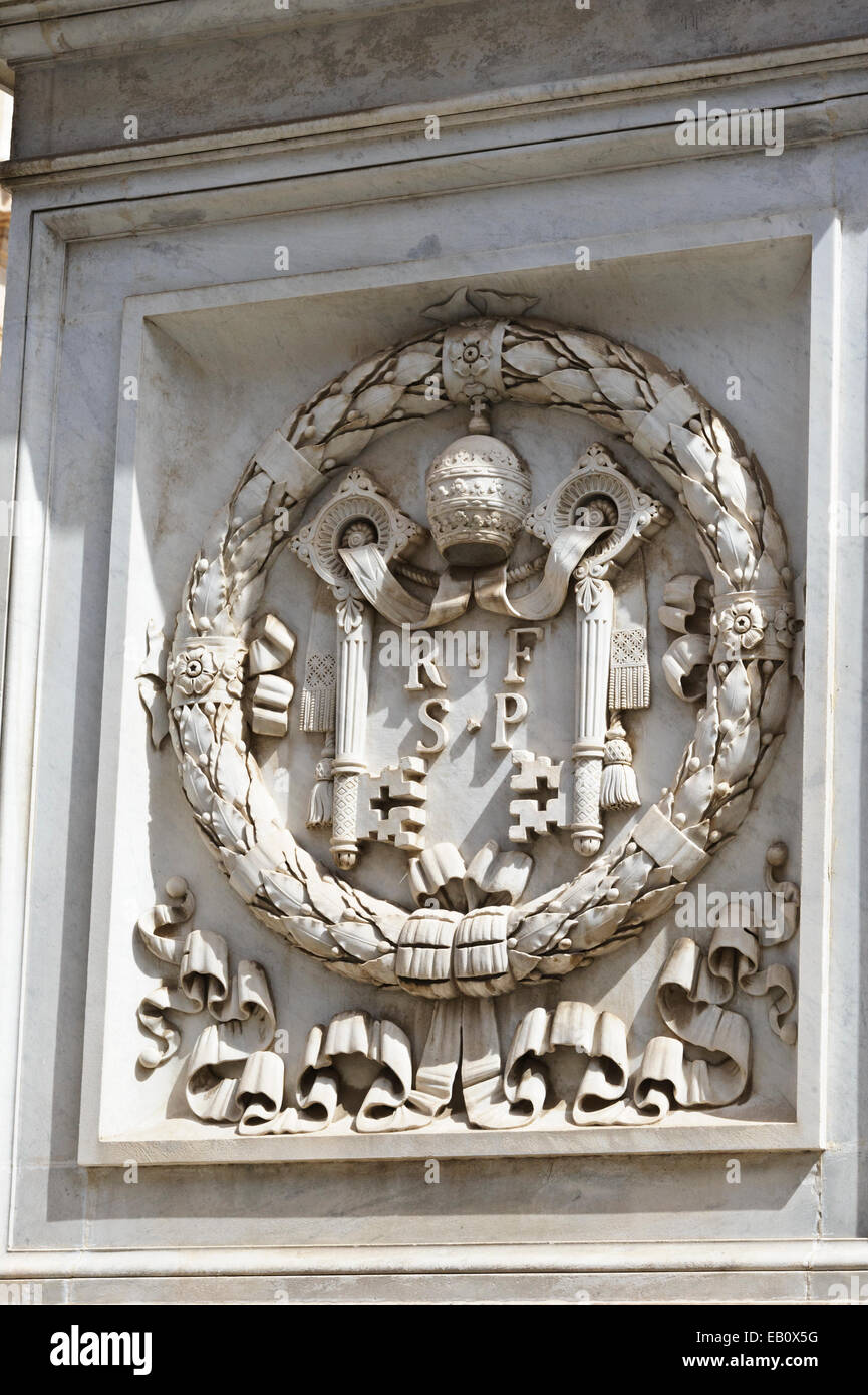 Stone carvings of the papal emblem on a white monument in the square in Vatican City, Rome ...