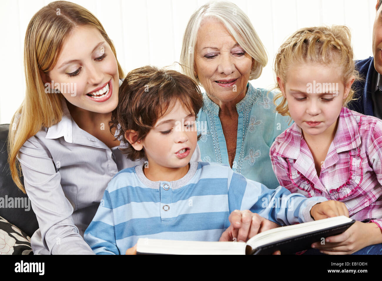 Happy family in three generations reading a book in the living room ...