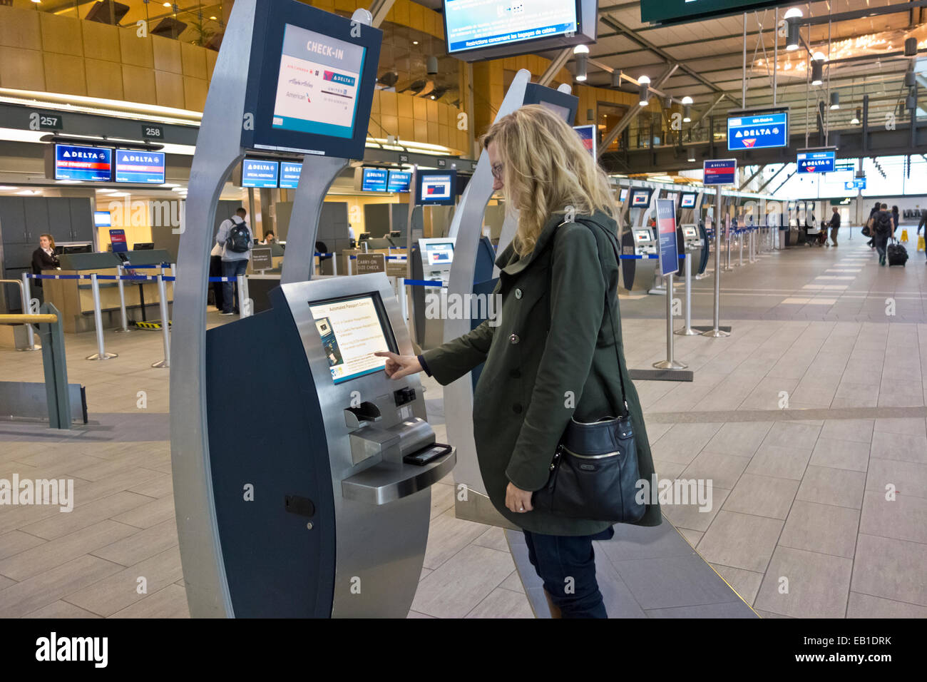 Woman using the electronic airline check-in kiosk at the Vancouver ...