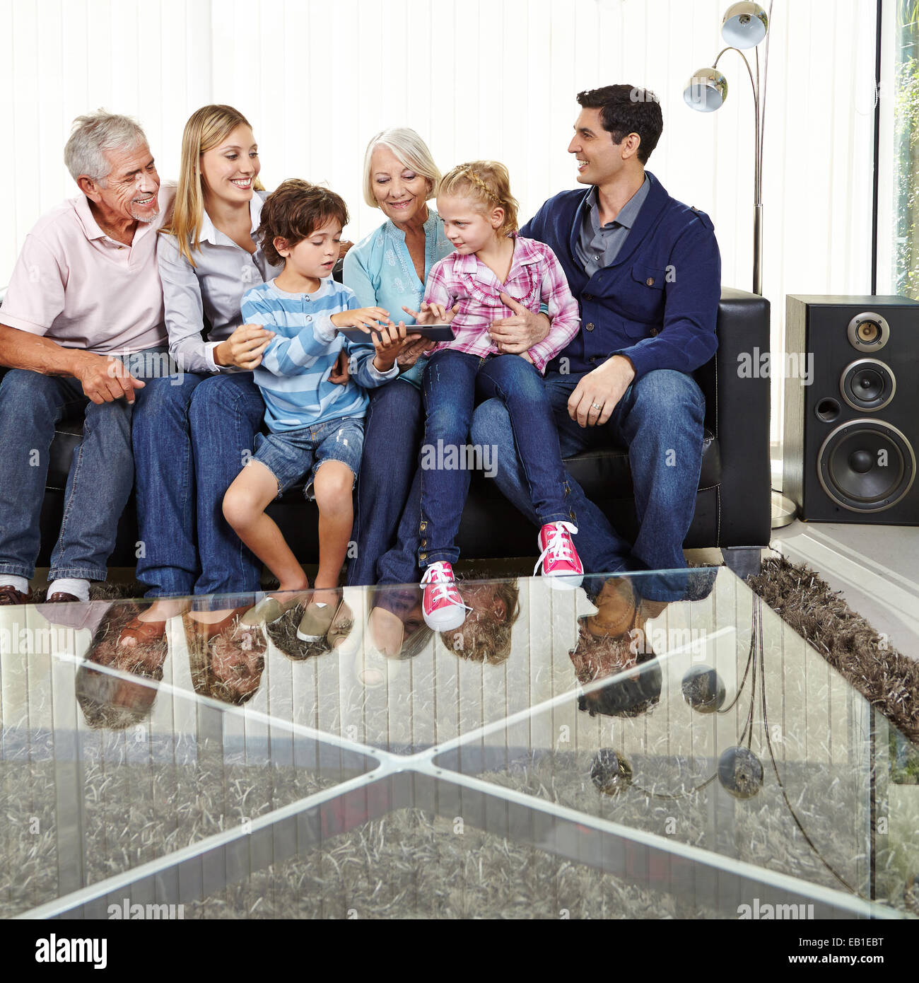 Two children playing with parents and grandparents with a tablet ...