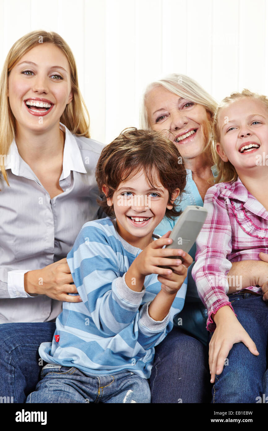 Happy family with remote control watching TV in living room Stock Photo ...