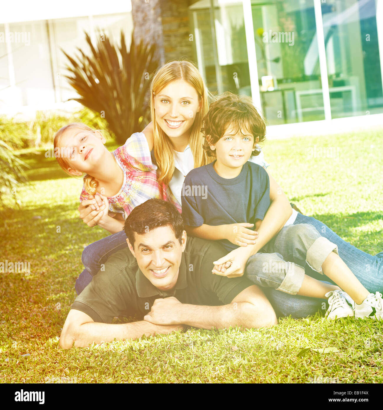 Happy family with two children laying in summer in front of a house ...