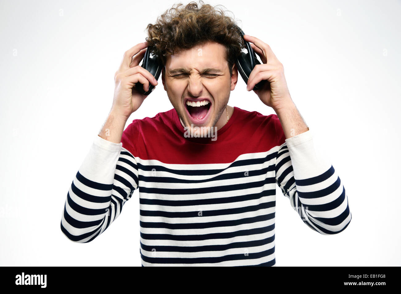 Man screaming while listening to music over gray background Stock Photo ...