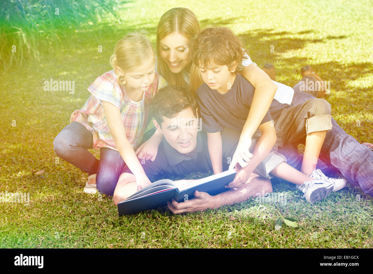 Happy family reading a book in garden in summer Stock Photo - Alamy
