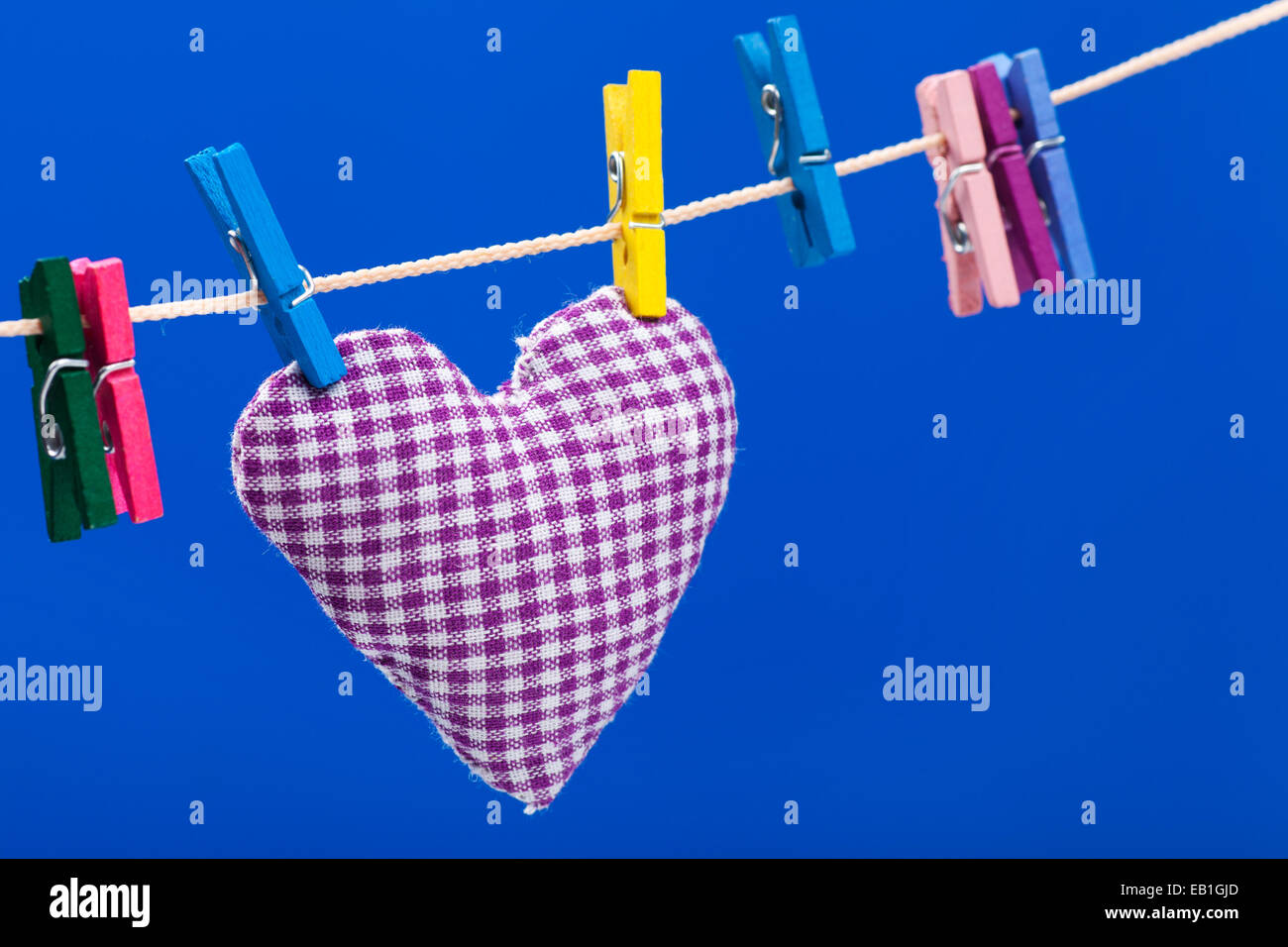 single heart on clothesline with clothespins, blue background Stock ...