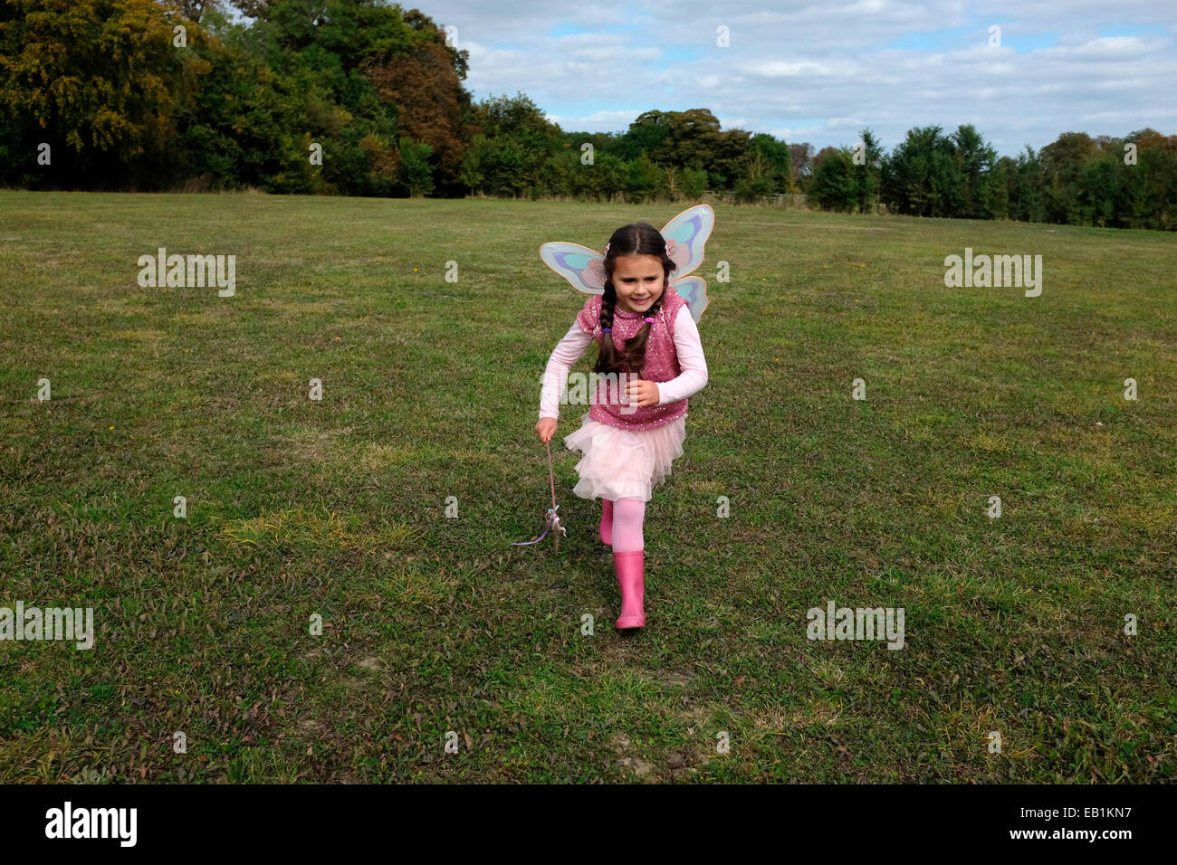 Young girl dressed as fairy running across a field Stock Photo - Alamy