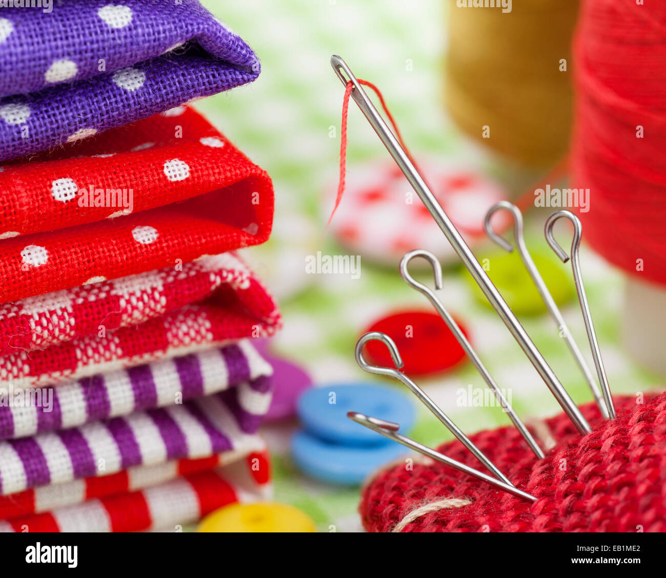 Sewing items: colorful fabrics, buttons, pin cushion, thimble, spool of ...