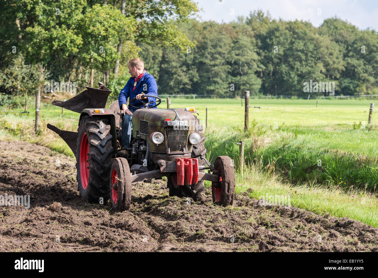 Farmer riding with an old tractor Stock Photo - Alamy