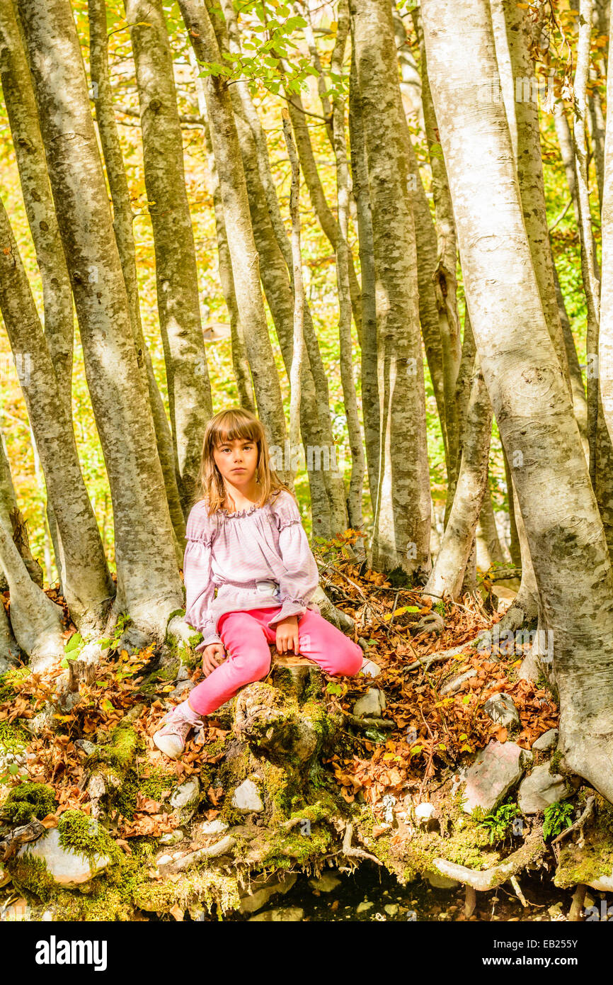 Little girl sitting on the tree trunk Stock Photo - Alamy