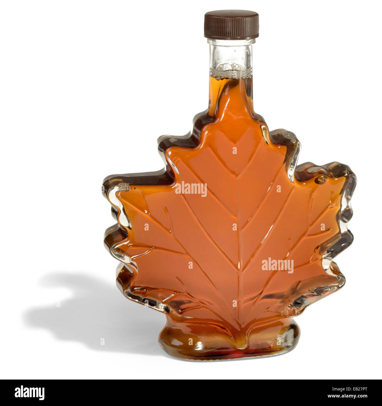 maple syrup in a leaf shaped glass bottle photographed on a white ...