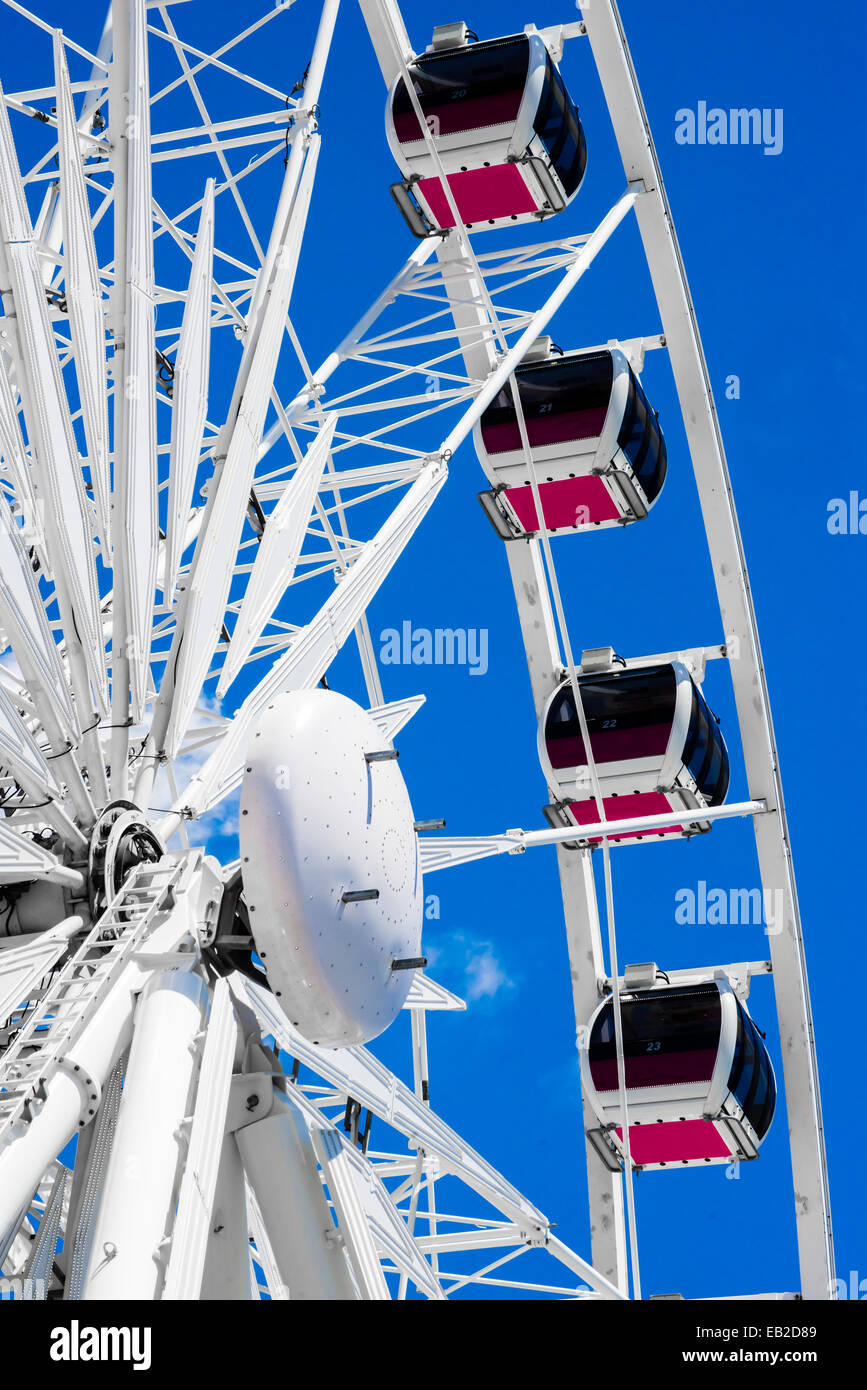 The pods of a white ferris wheel photographed against a very blue sky ...
