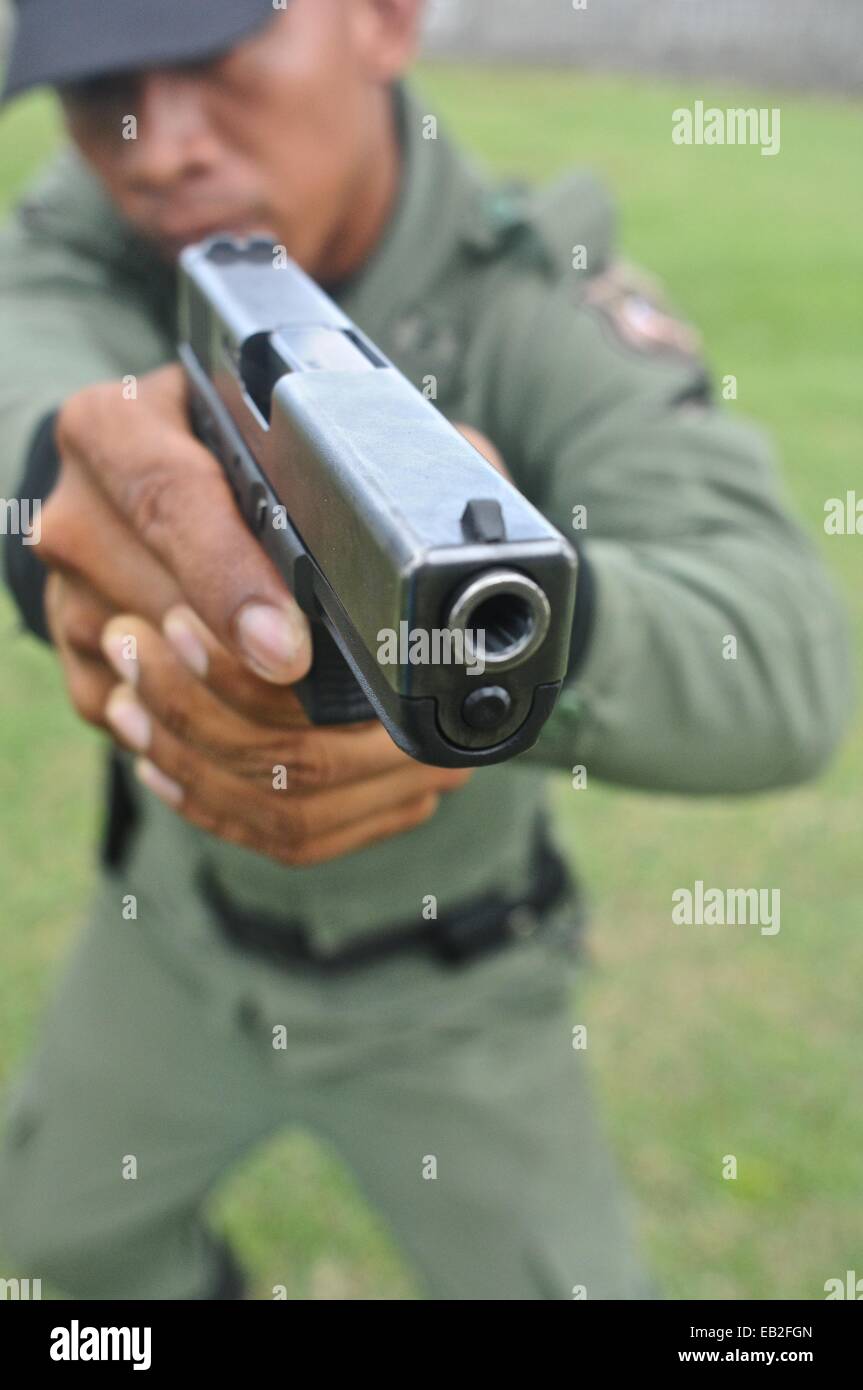 Uniformed police officer aiming a pistol at a tactical and firearms ...