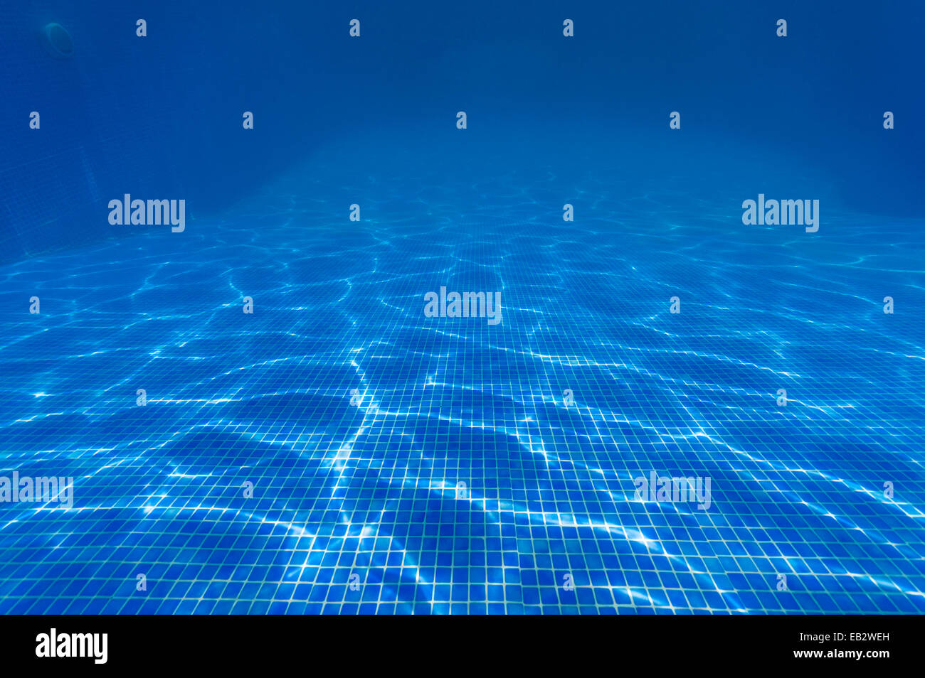Sun ray patterns on the tiled bottom of a swimming pool at a tropical ...