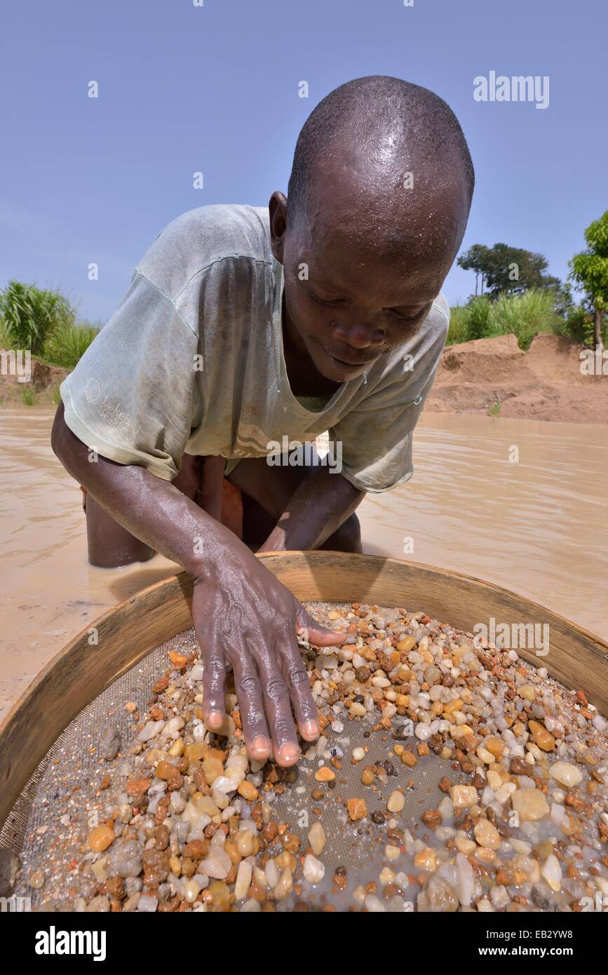Diamond hunter searching for diamonds with a sieve, near Koidu, Koidu ...
