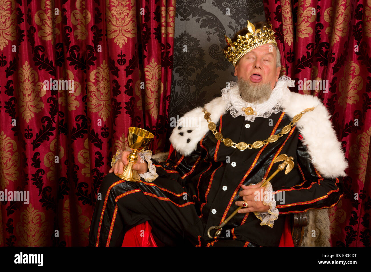 Old funny king getting drunk holding a golden goblet Stock Photo - Alamy