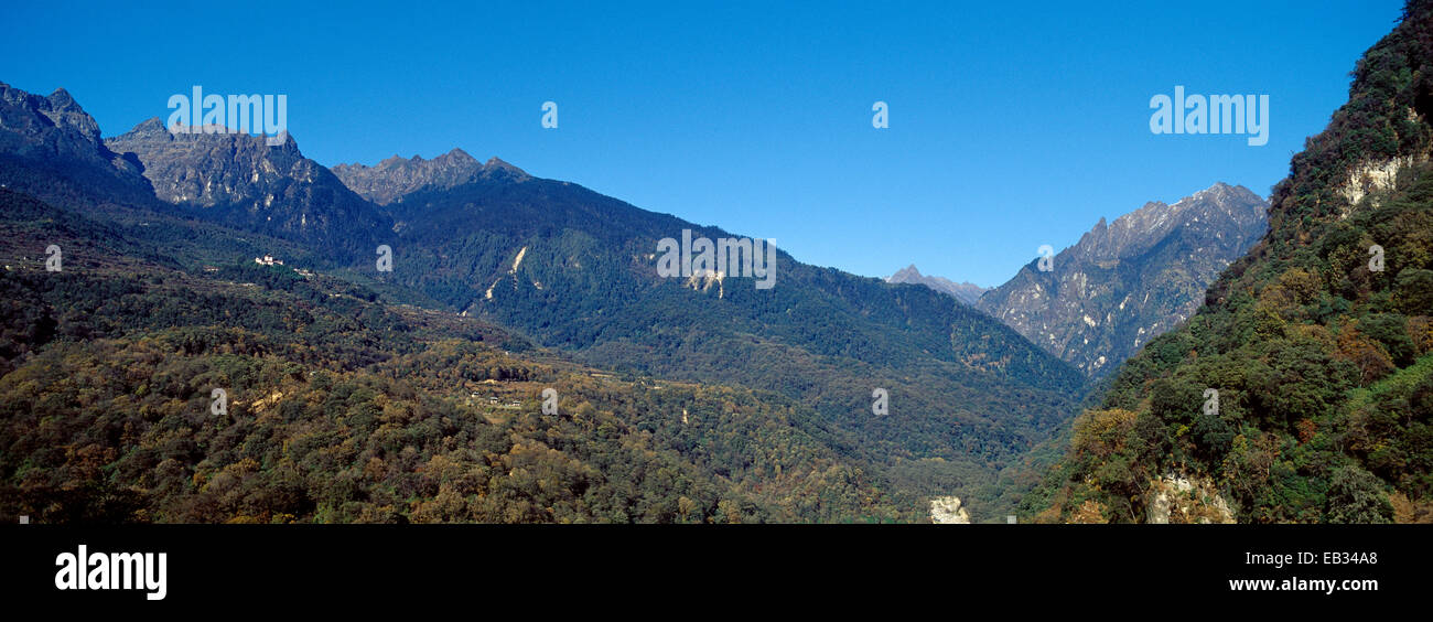 A rugged Himalayan mountain ridge above a small village in a dense ...