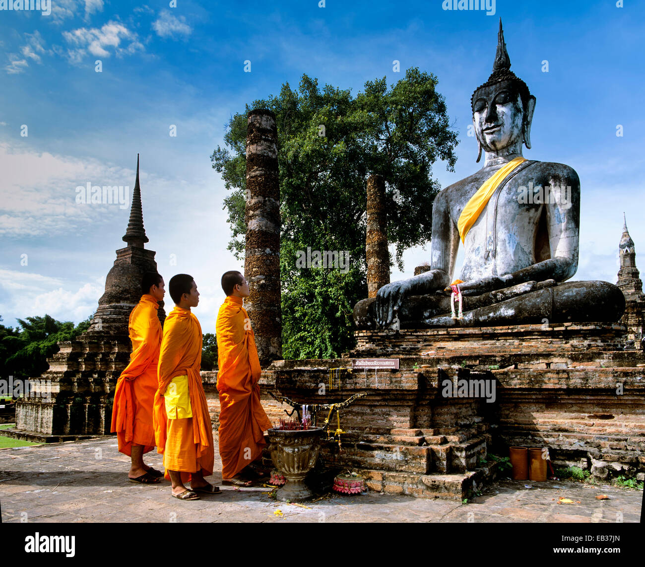 Three monks standing in front of the seated Buddha at Wat Mahathat ...