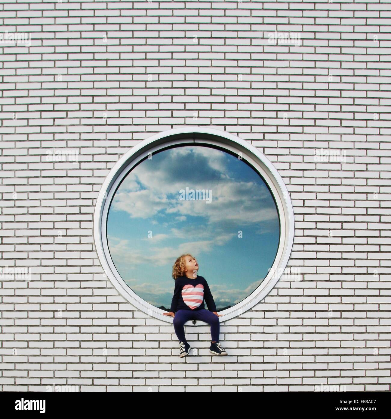 Girl sitting on a window sill looking up at the sky Stock Photo - Alamy