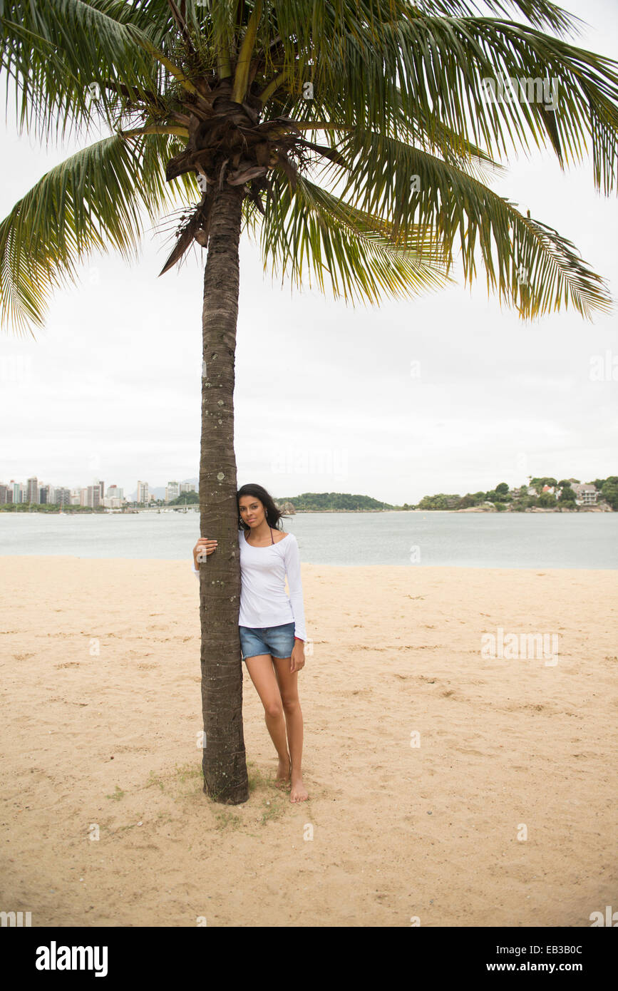 Smiling woman hugging palm tree on tropical beach Stock Photo - Alamy