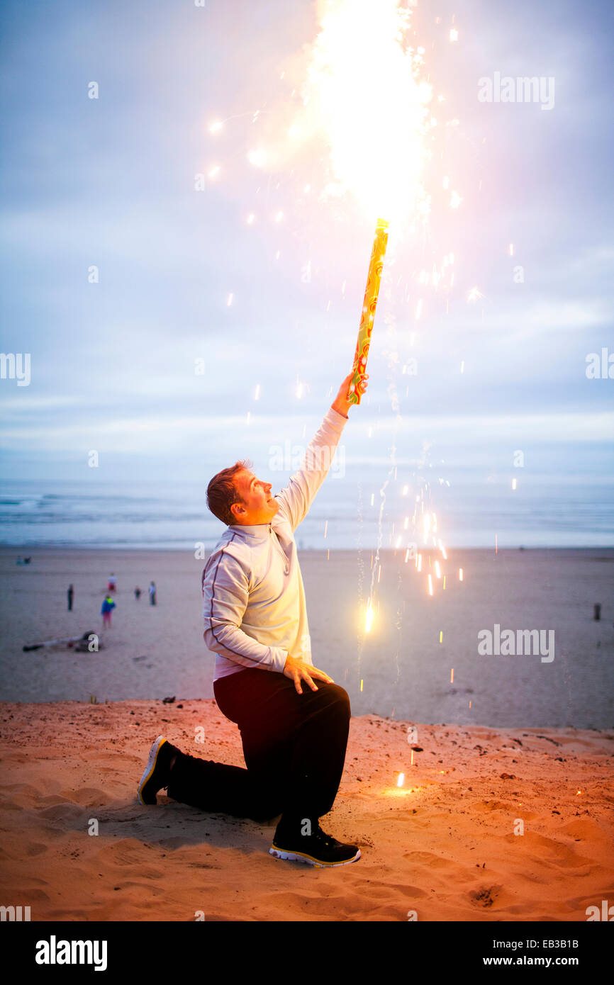 Caucasian man holding fireworks on beach Stock Photo - Alamy