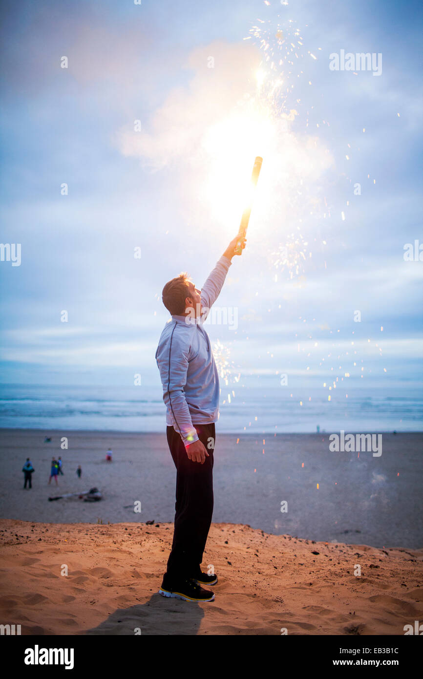 Caucasian man holding fireworks on beach Stock Photo - Alamy