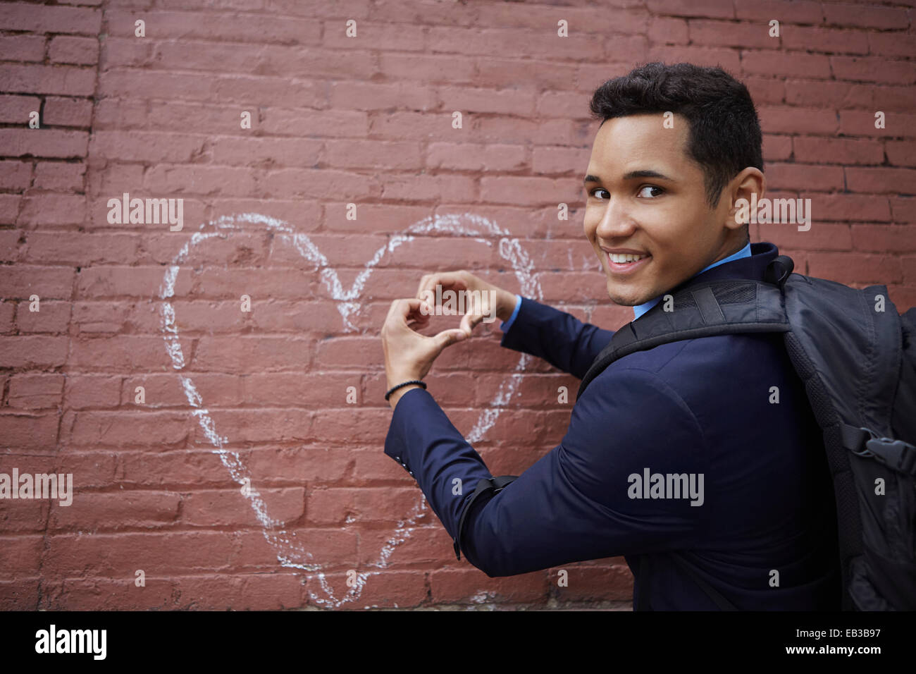 Smiling man making heart shape with hands by heart chalk drawing on ...